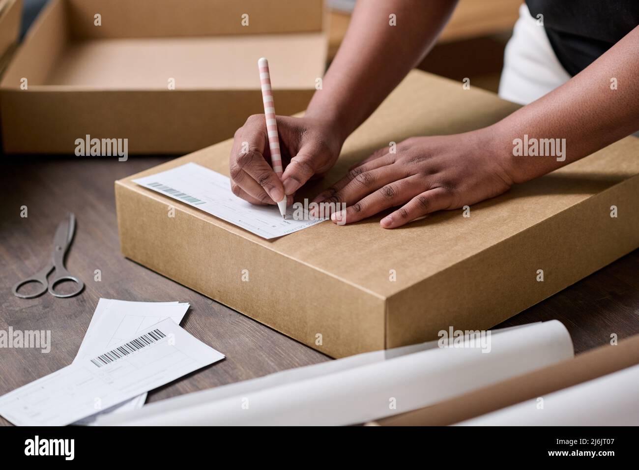 Hands of young black woman with pen writing down address of client on ...