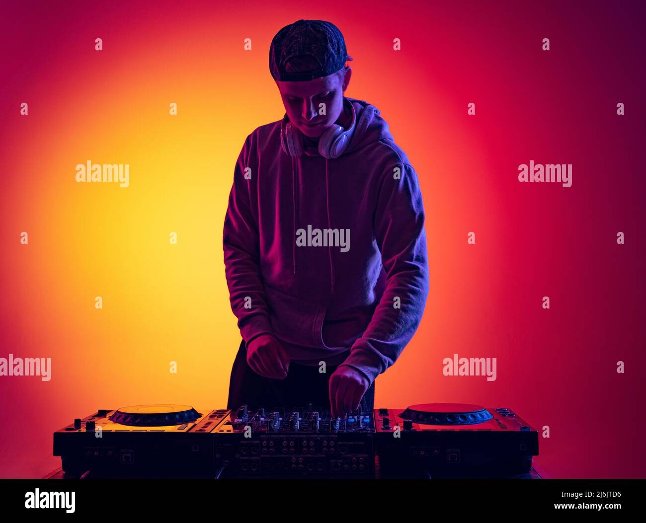 Portrait of young man making sounds with professional dj mixer isolated ...