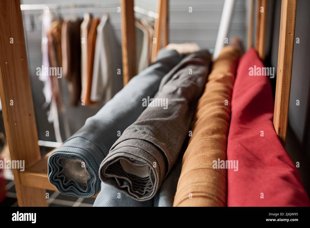 Stack of rolls of several natural textiles of various colors on wooden ...