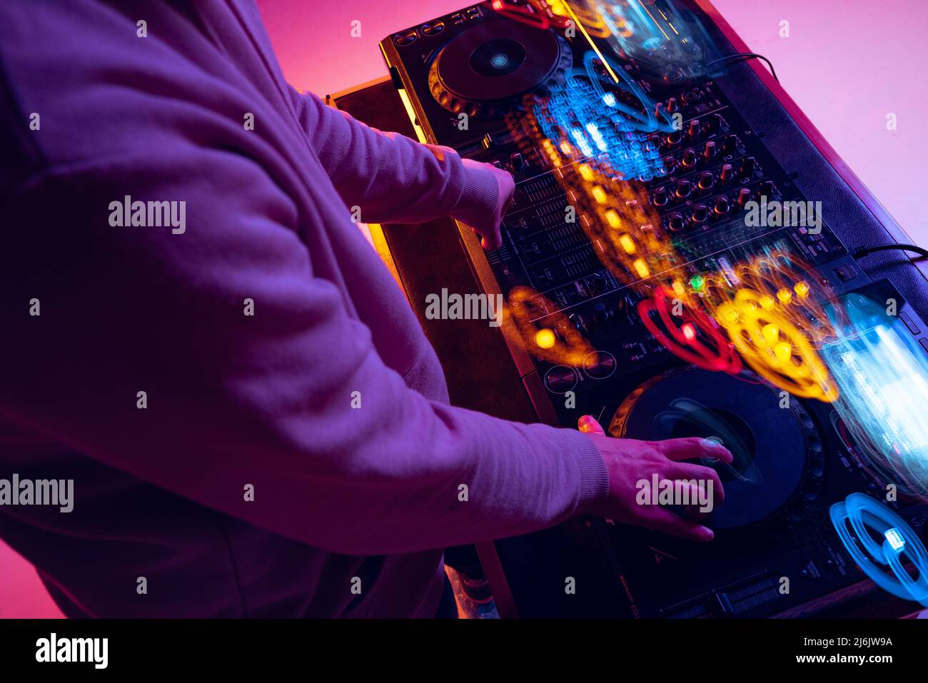 Close-up image of male hands, dj making sounds at night club party with ...