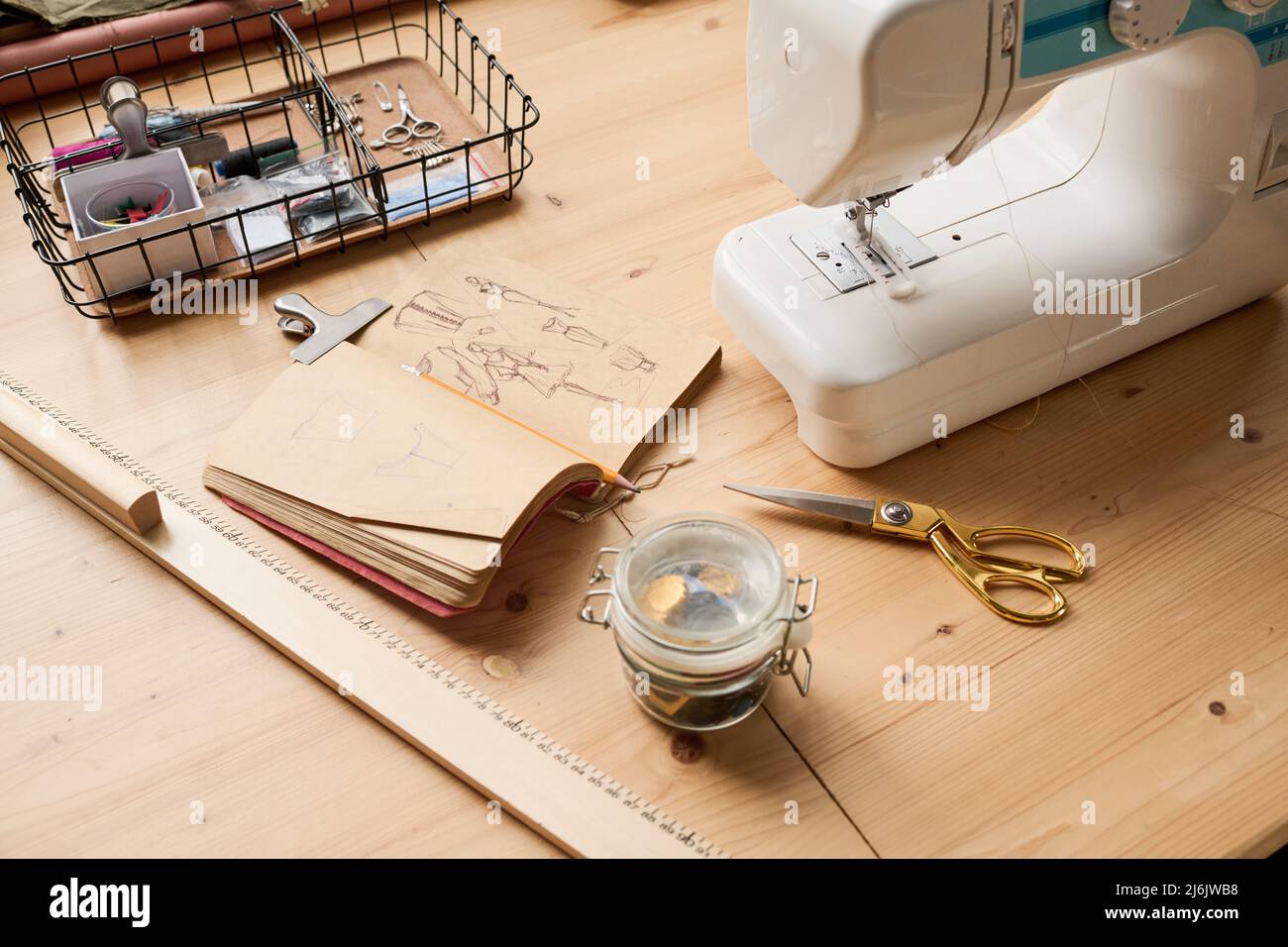Part of wooden table with electric sewing machine, ruler, scissors ...