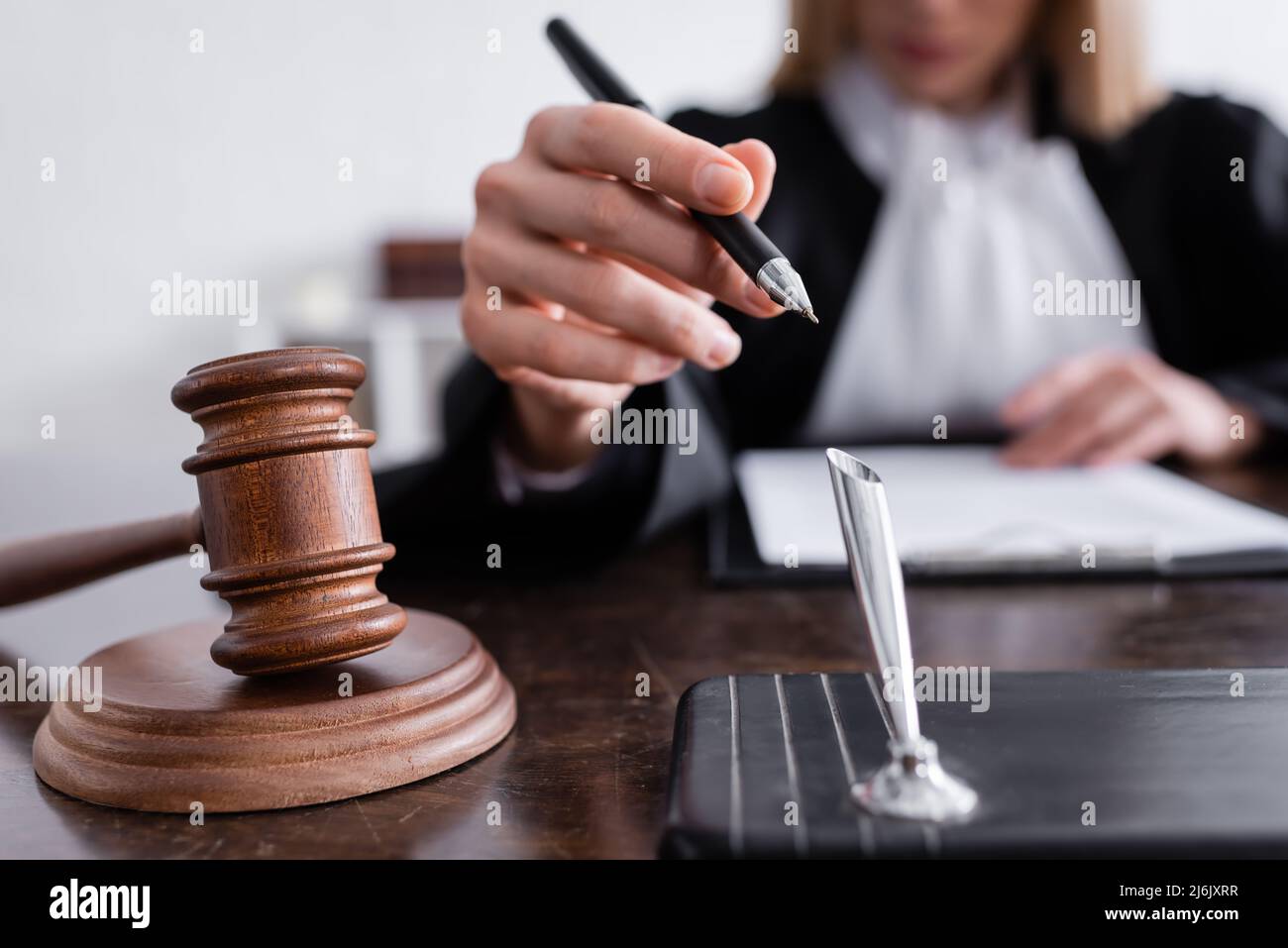 selective focus of wooden gavel near cropped prosecutor with pen on ...