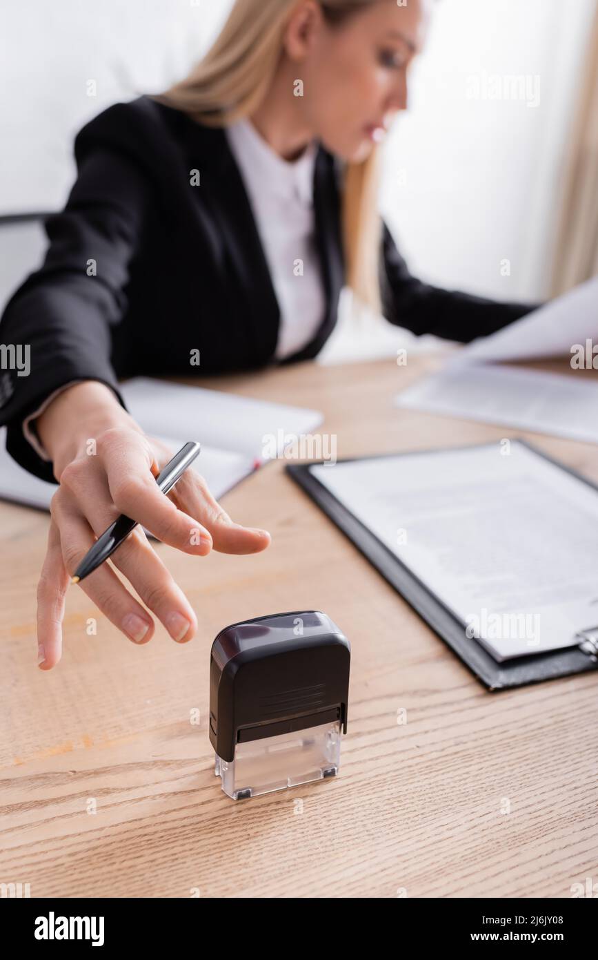 lawyer reaching stamper while working with documents on blurred ...