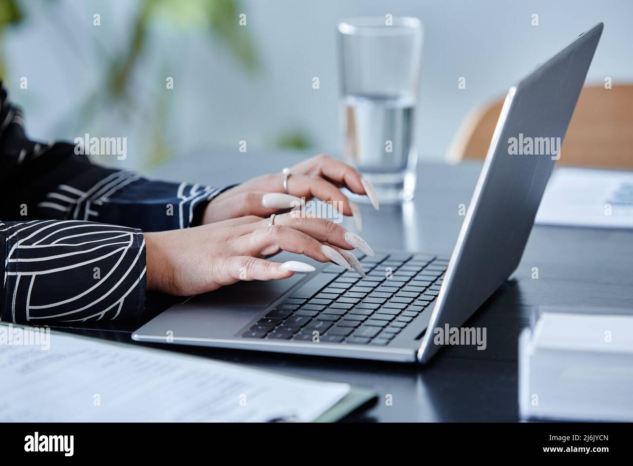 Close up of young black woman with long manicure typing at laptop ...