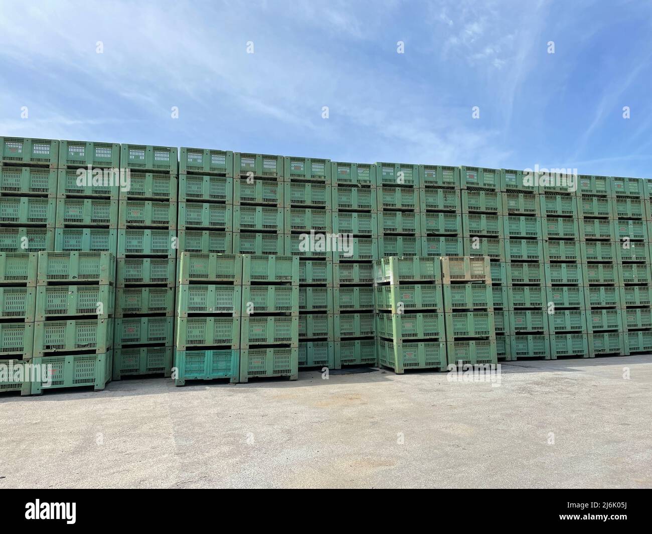 Huge stack of plastic crates of solid green color outside storage of ...