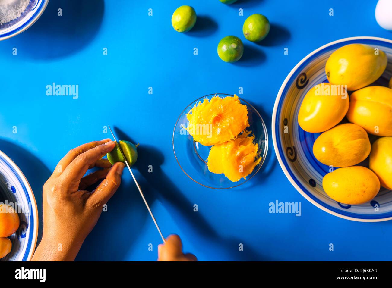 Top view of a latin woman's hand cutting a lemon on a blue surface with ...
