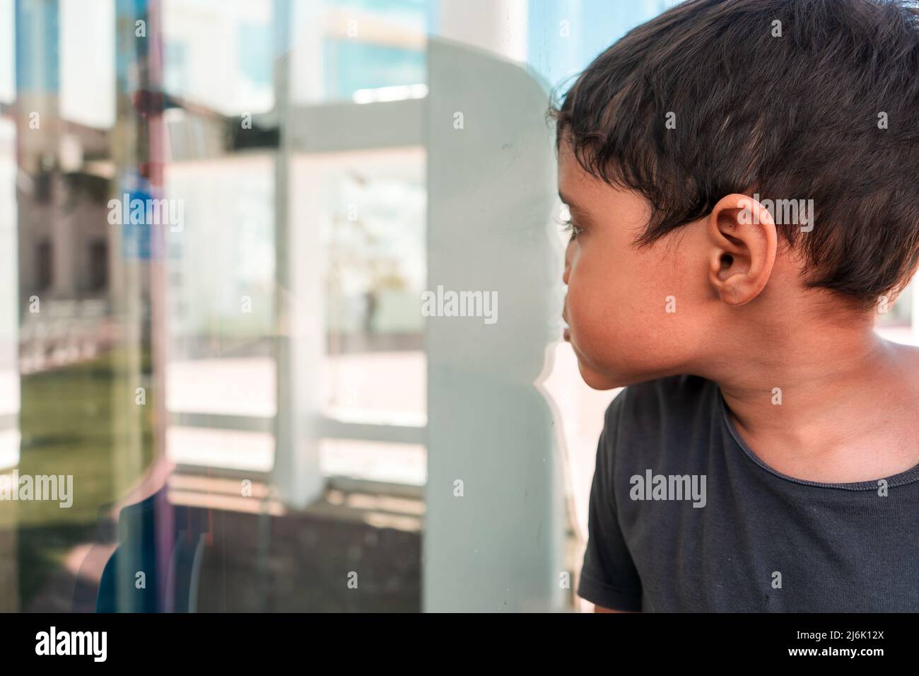 Latino boy pressing his face against glass outdoors. Concept of self ...