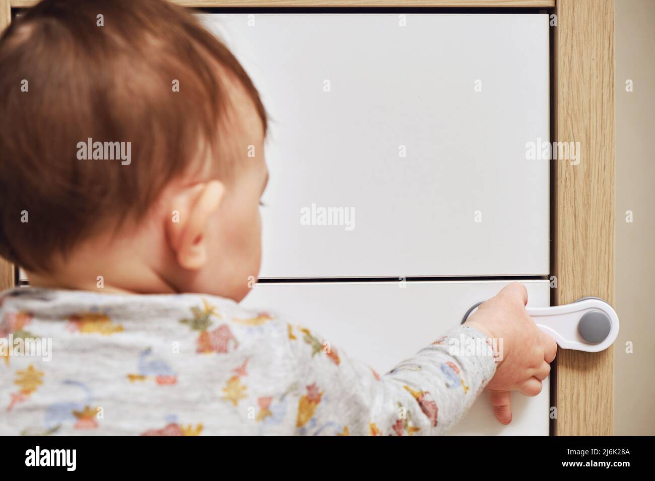 Toddler baby boy rips off a cabinet drawer with his hand. The child ...