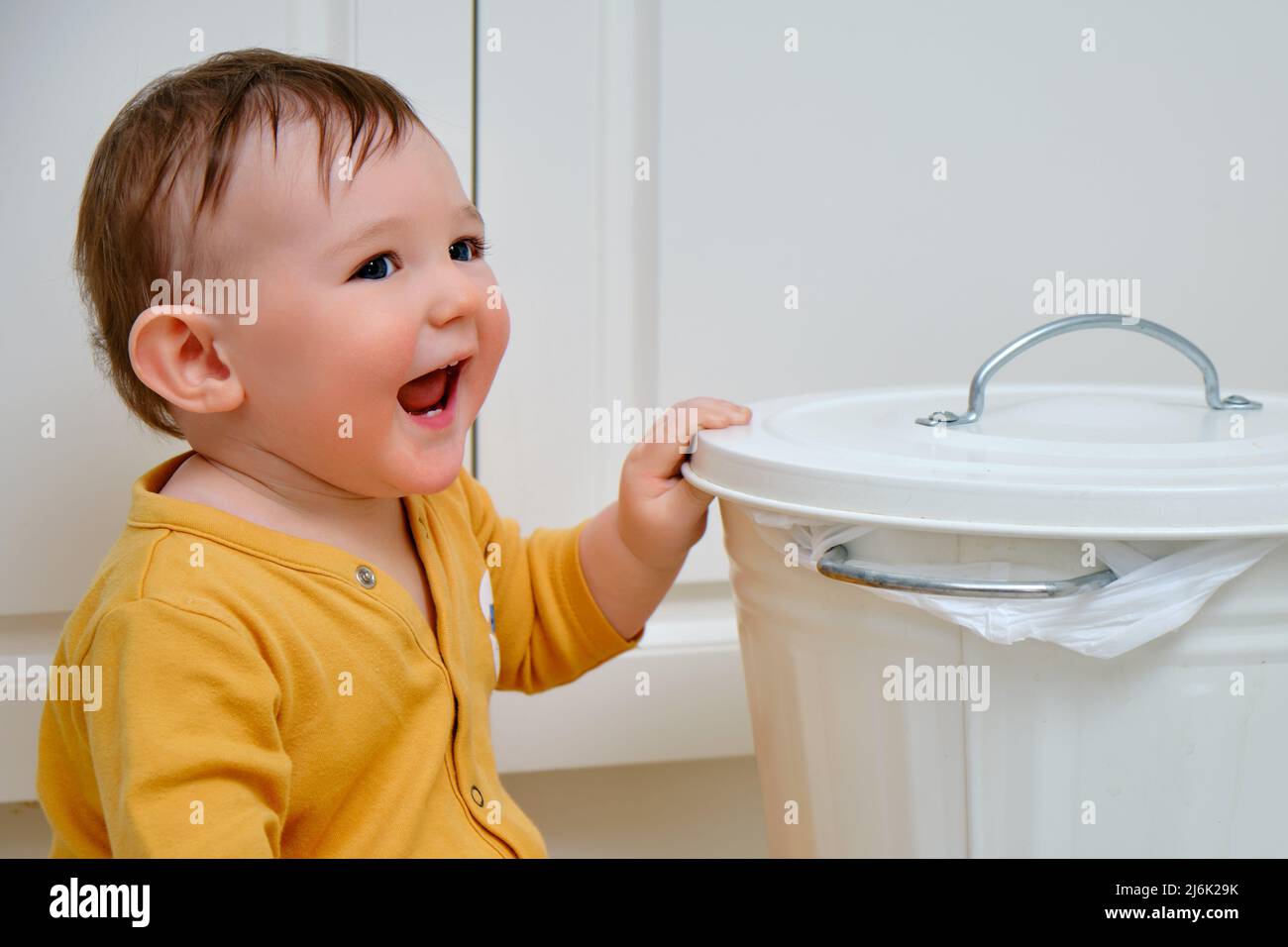 Toddler baby boy opens a trash can with household waste. Children's ...
