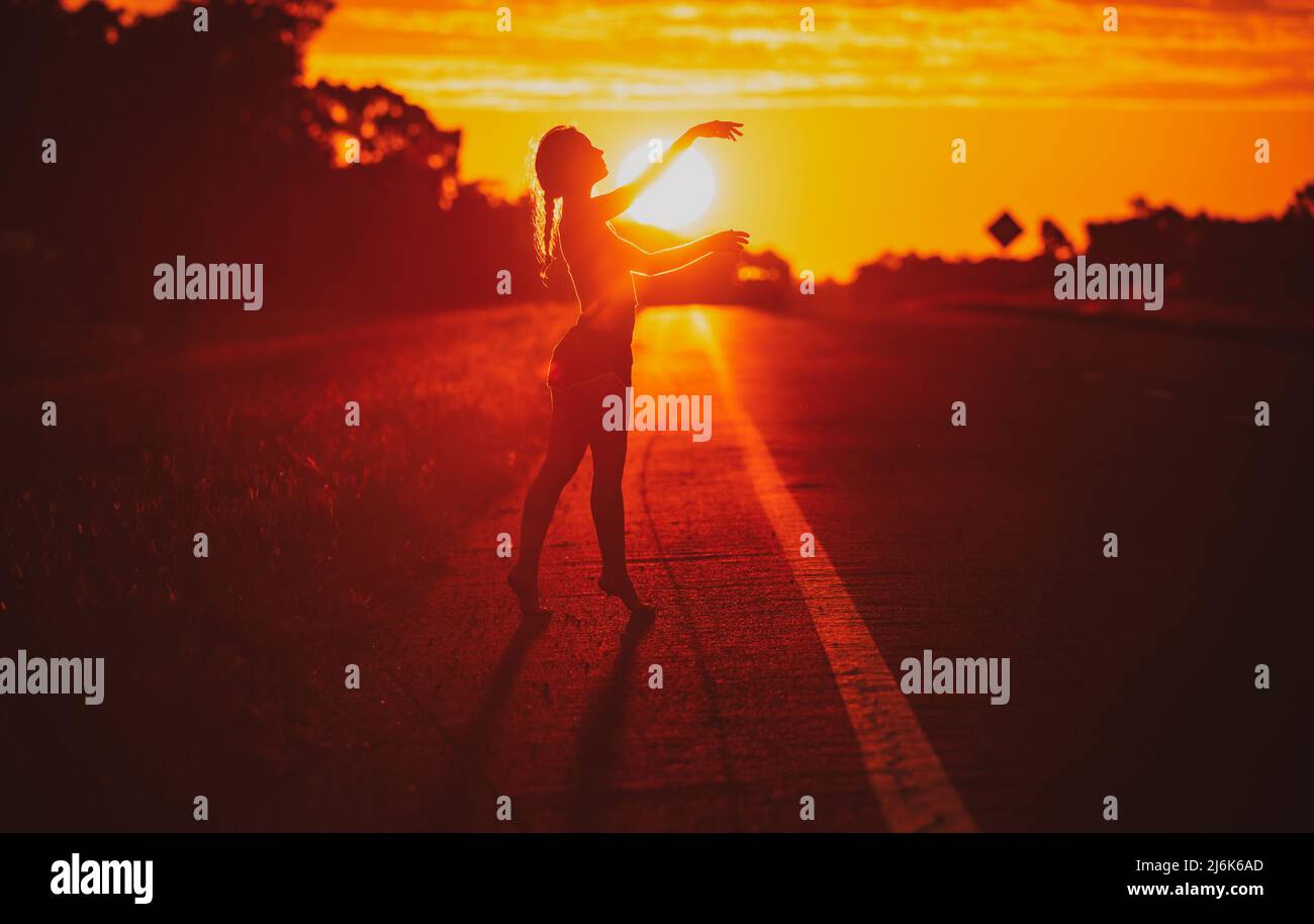 Young woman dancing in summer sunset sky outdoor. People freedom style ...
