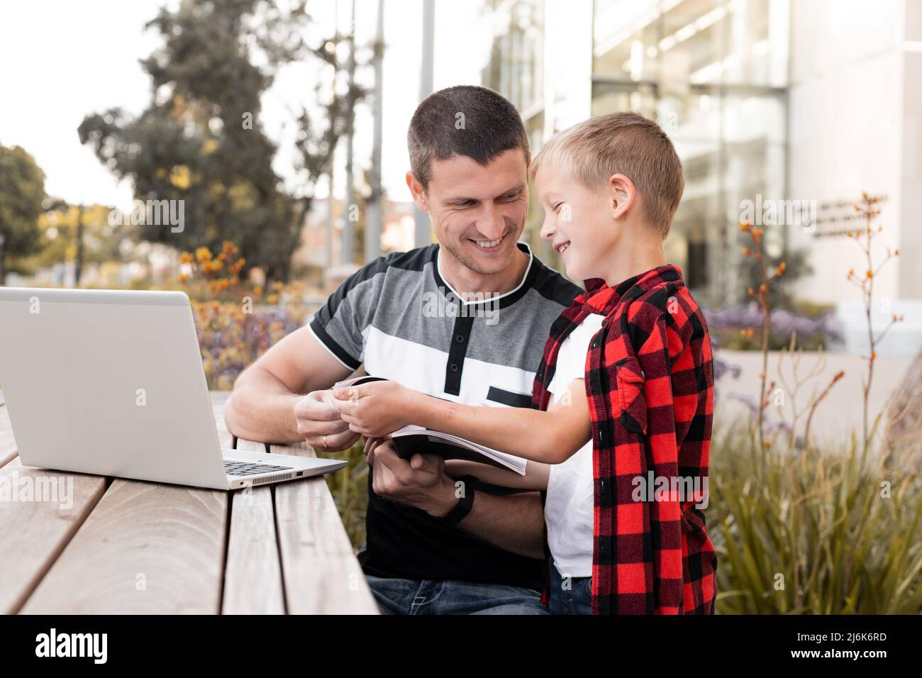 Young dad and son or teacher and student communicate and check homework ...