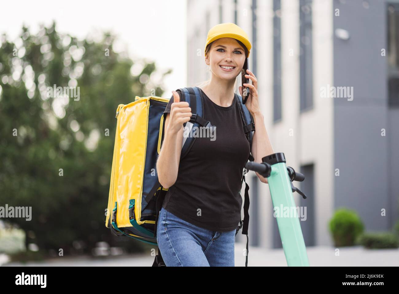 Delivery woman using smartphone while standing in the city with ...