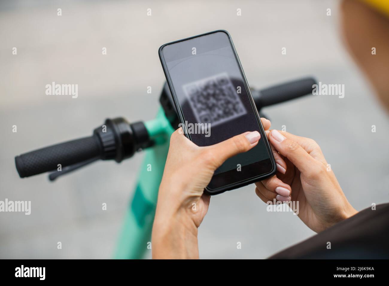 Woman scan QR code by smart phone to unlock and rent electric push ...