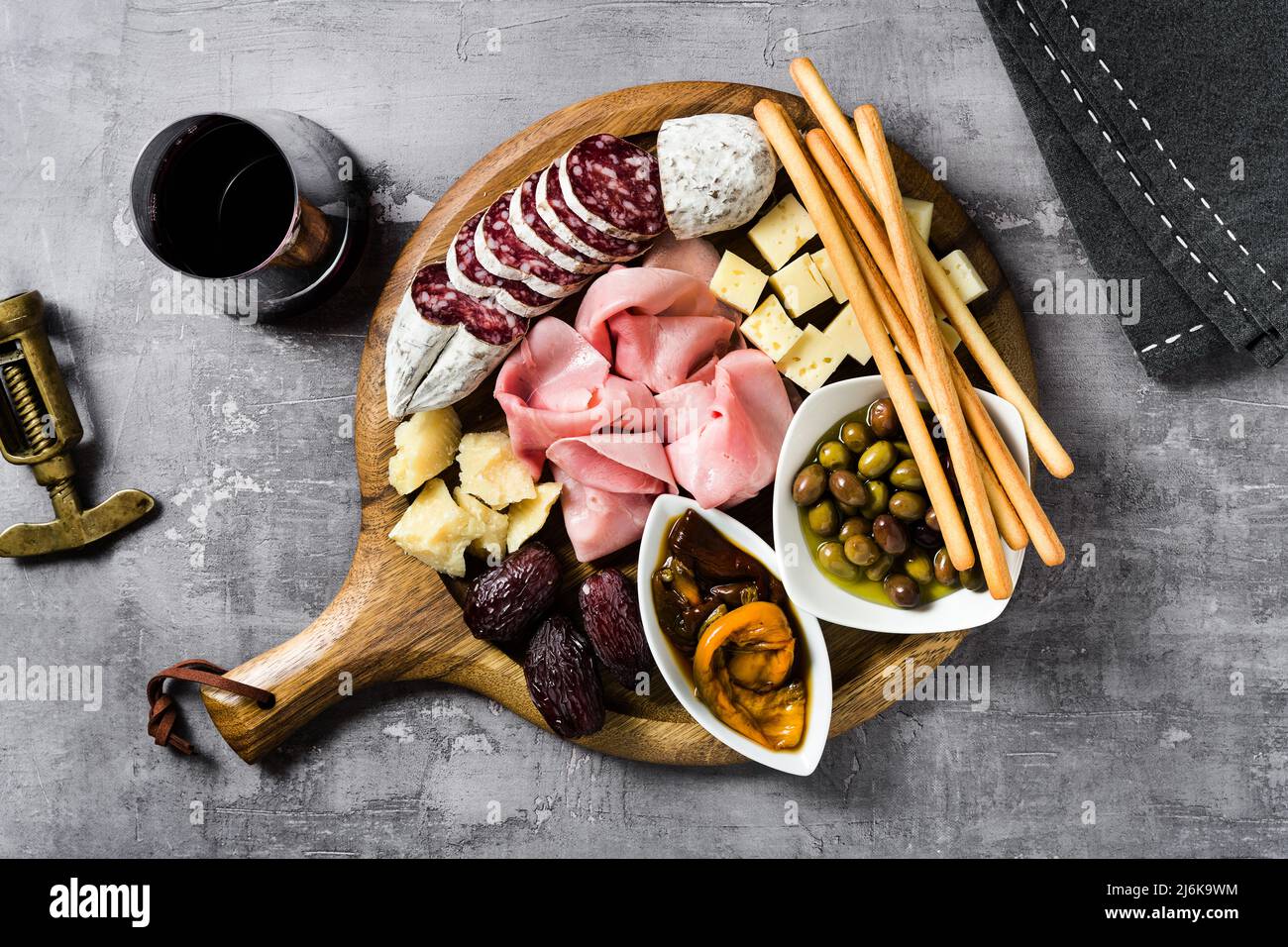 Italian snack and antipasti on a tray and red wine: prosciutto, salami ...