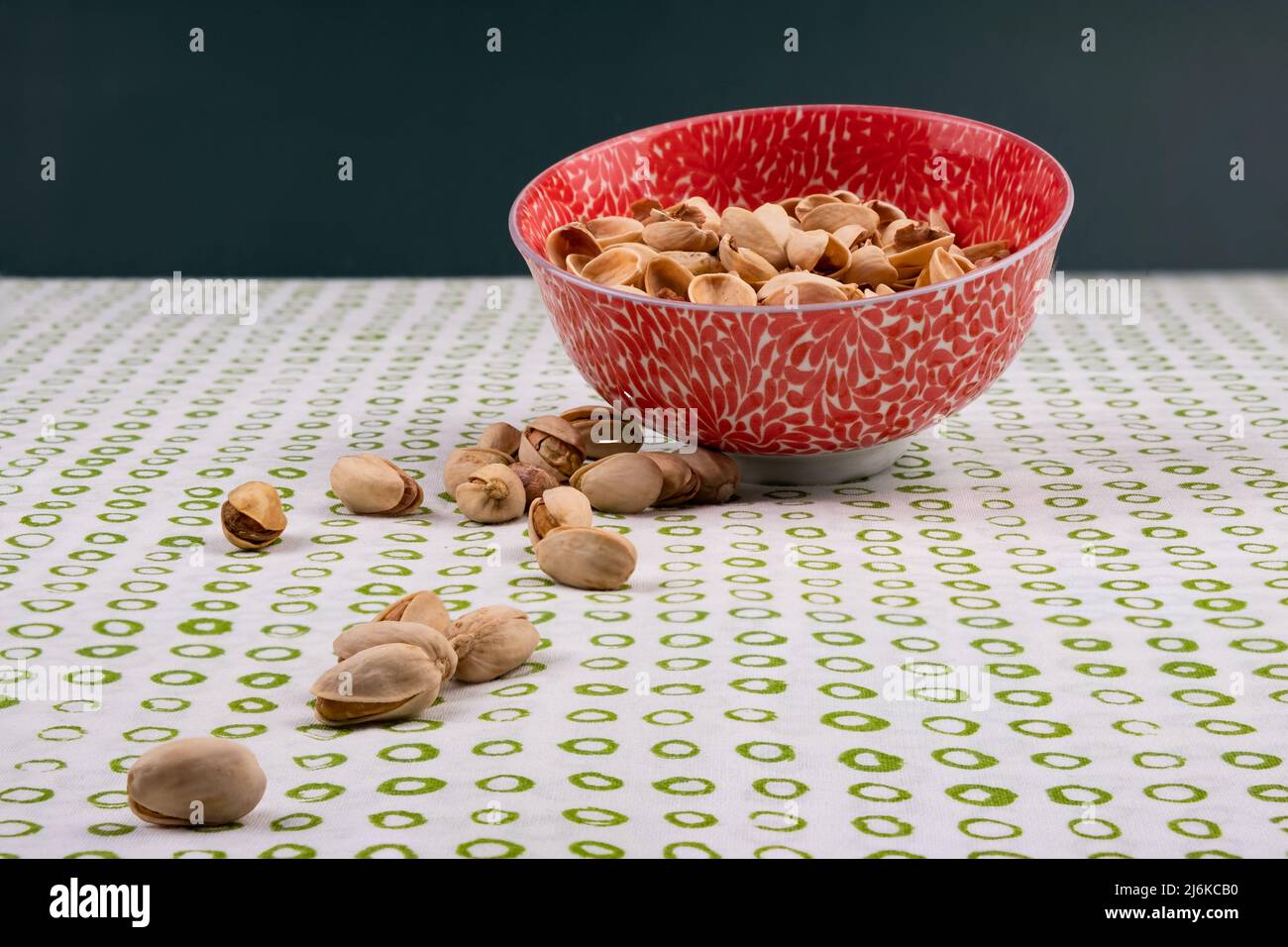 Organic pistachio shells in a flowery bowl on top of a white table with ...