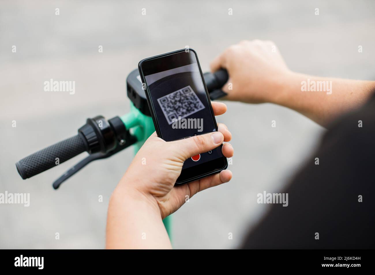 Man scan QR code by smart phone to unlock and rent electric push ...