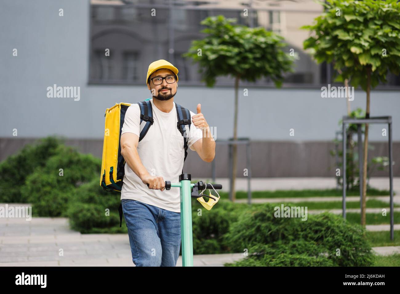 Food delivery electric scooter driver with yellow backpack behind back ...