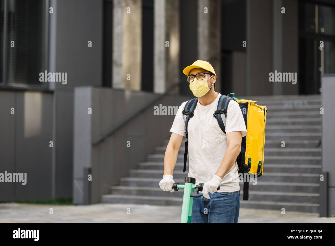 Courier deliver food on electric scooter wearing yellow facial ...