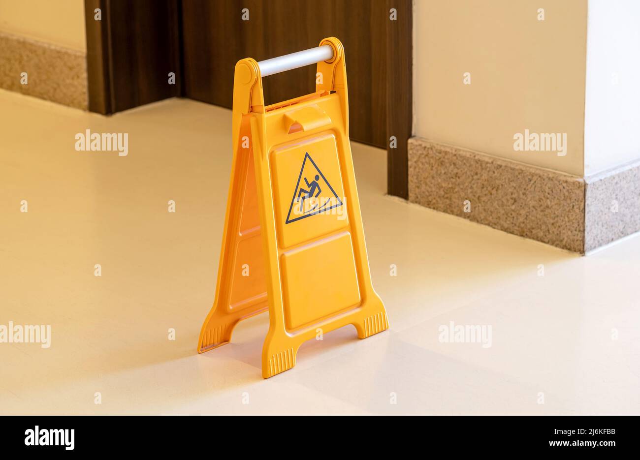 One orange caution slippery wet floor fold out sign in the hallway ...
