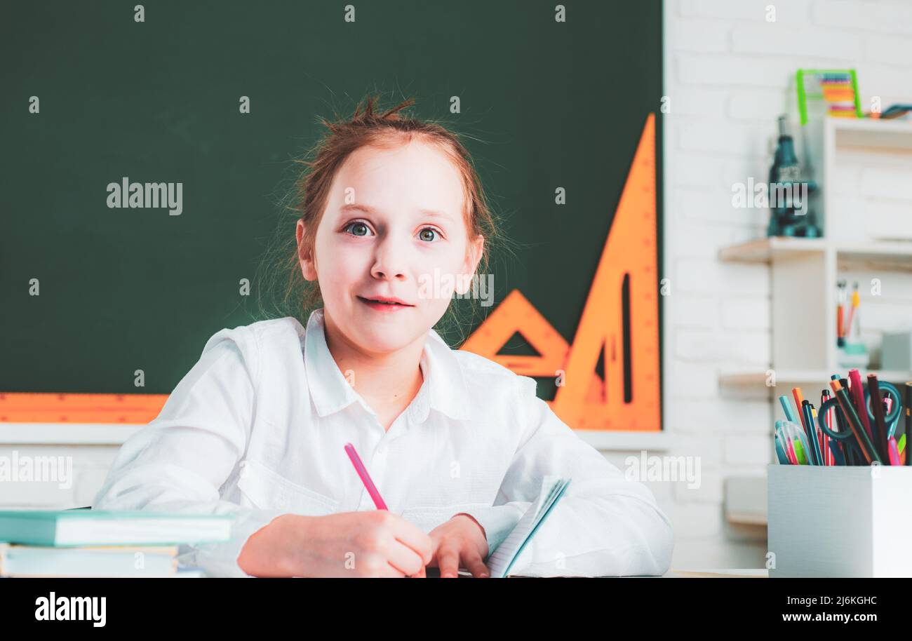 Little girl pupil with happy face expression near desk with school ...