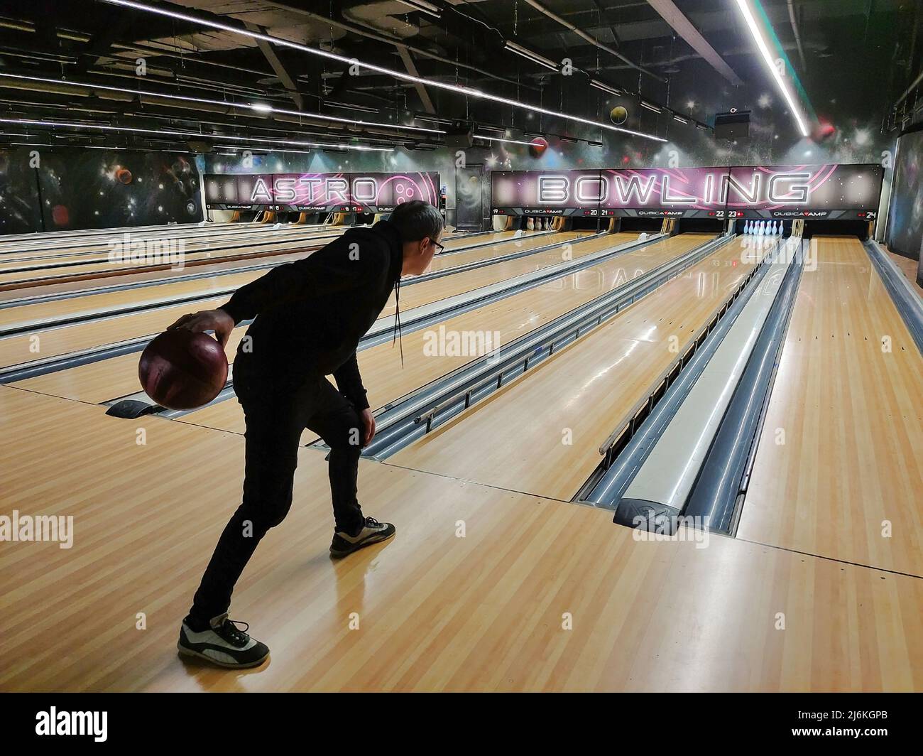 A man plays bowling, swings and throws the ball into the skittles. Back ...