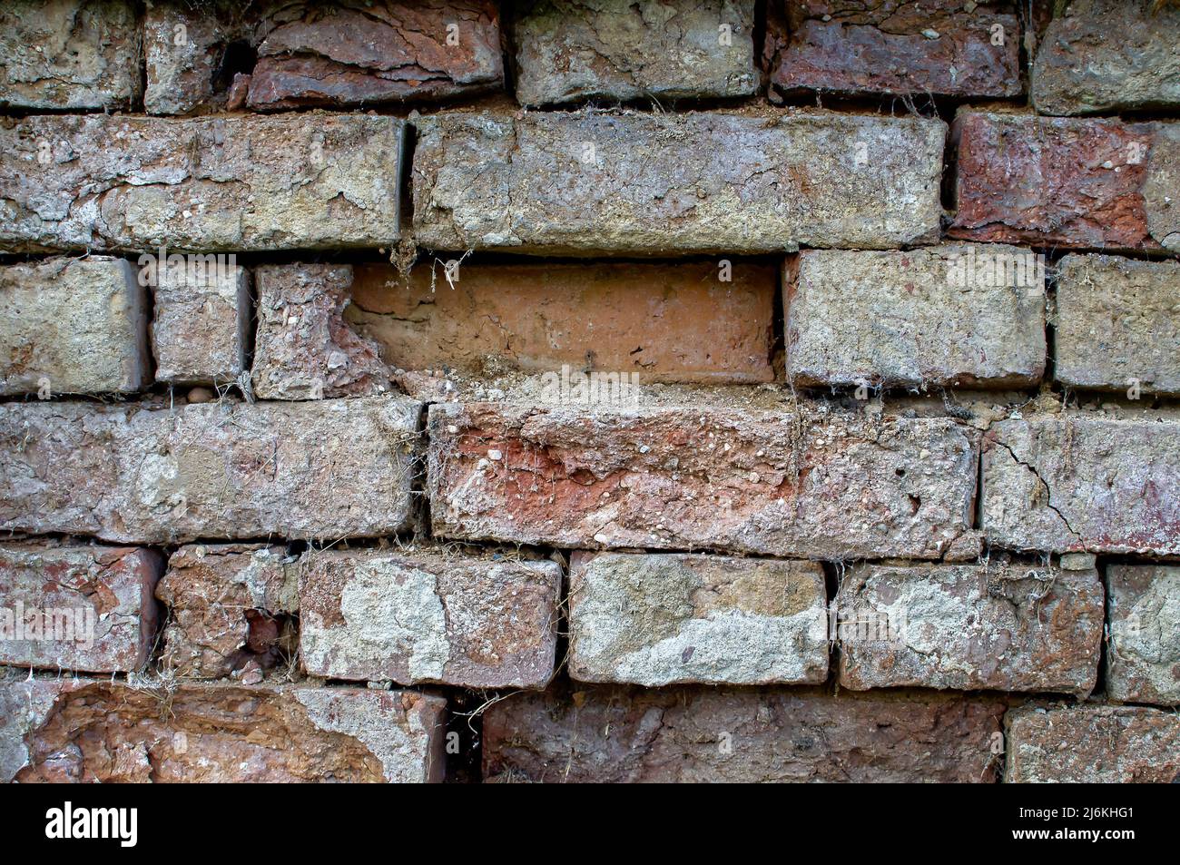 texture of an old wall, a wall made of damaged colored brick, with ...