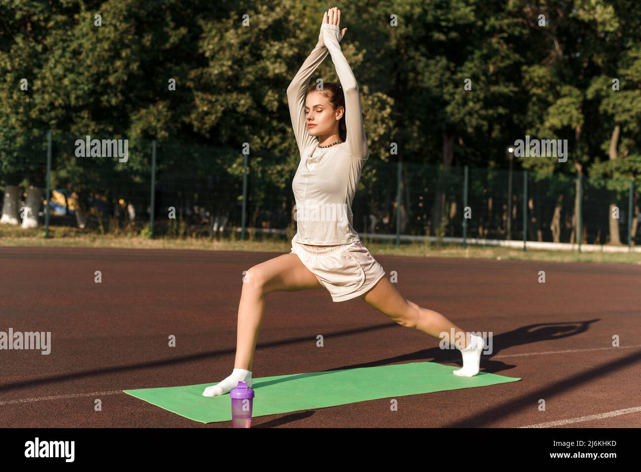 Young beautiful sports model stretches out at the outdoors stadium in ...
