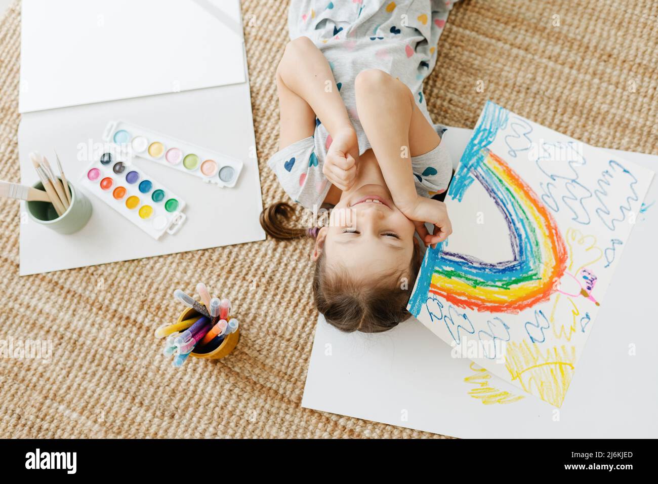 Child lying on floor and hold her draw with rainbow Stock Photo - Alamy