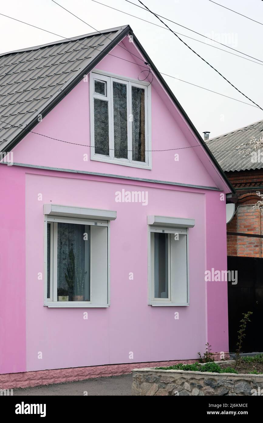 Pink facade of a one-story house with a triangular roof. Plastic ...