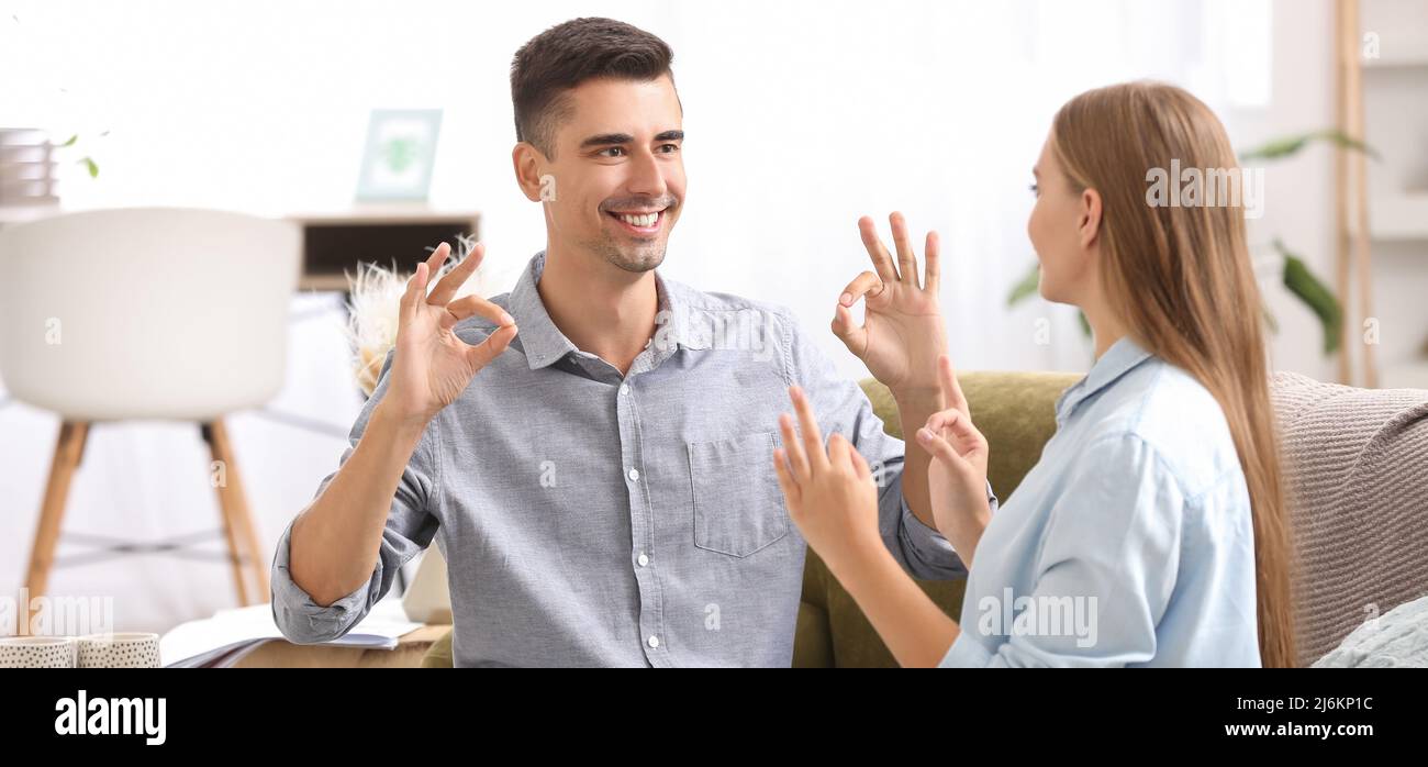 Young deaf mute couple using sign language at home Stock Photo - Alamy