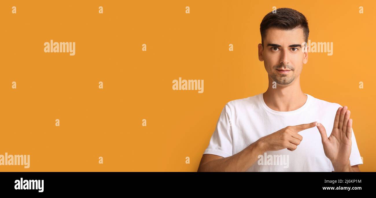Young deaf mute man using sign language on orange background with space ...