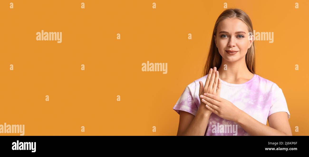 Young deaf mute woman using sign language on orange background with ...