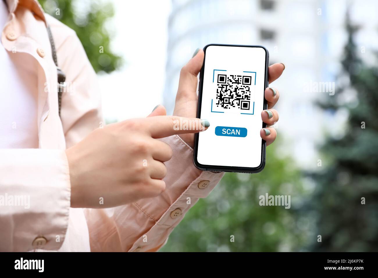 Woman holding smartphone with QR code on screen outdoors, closeup Stock ...