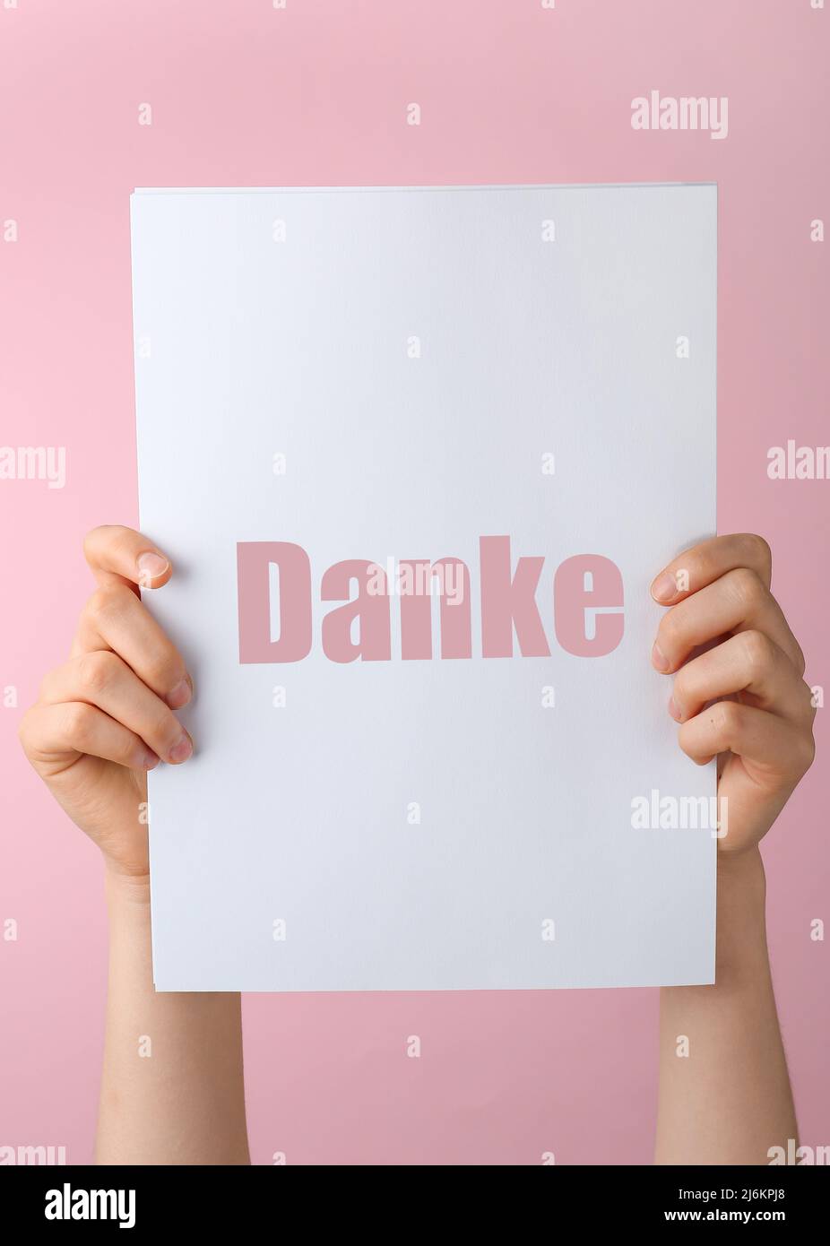 Female hands holding paper with word DANKE (German for Thanks) on pink ...