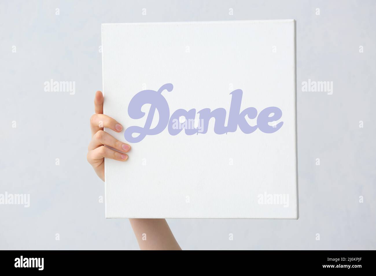 Female hand holding paper with word DANKE (German for Thanks) on light ...