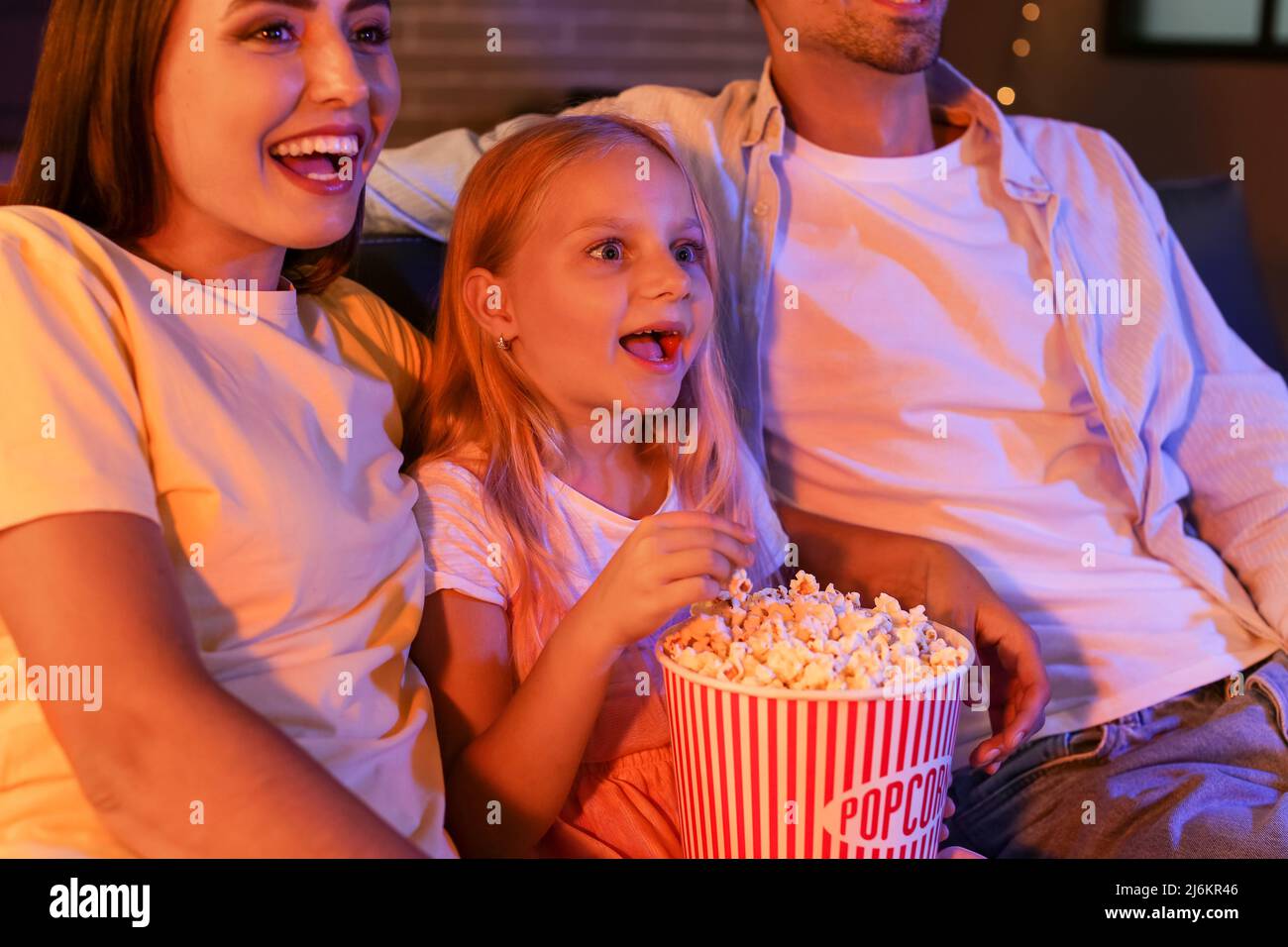 Happy family with popcorn watching movie at home in evening Stock Photo ...