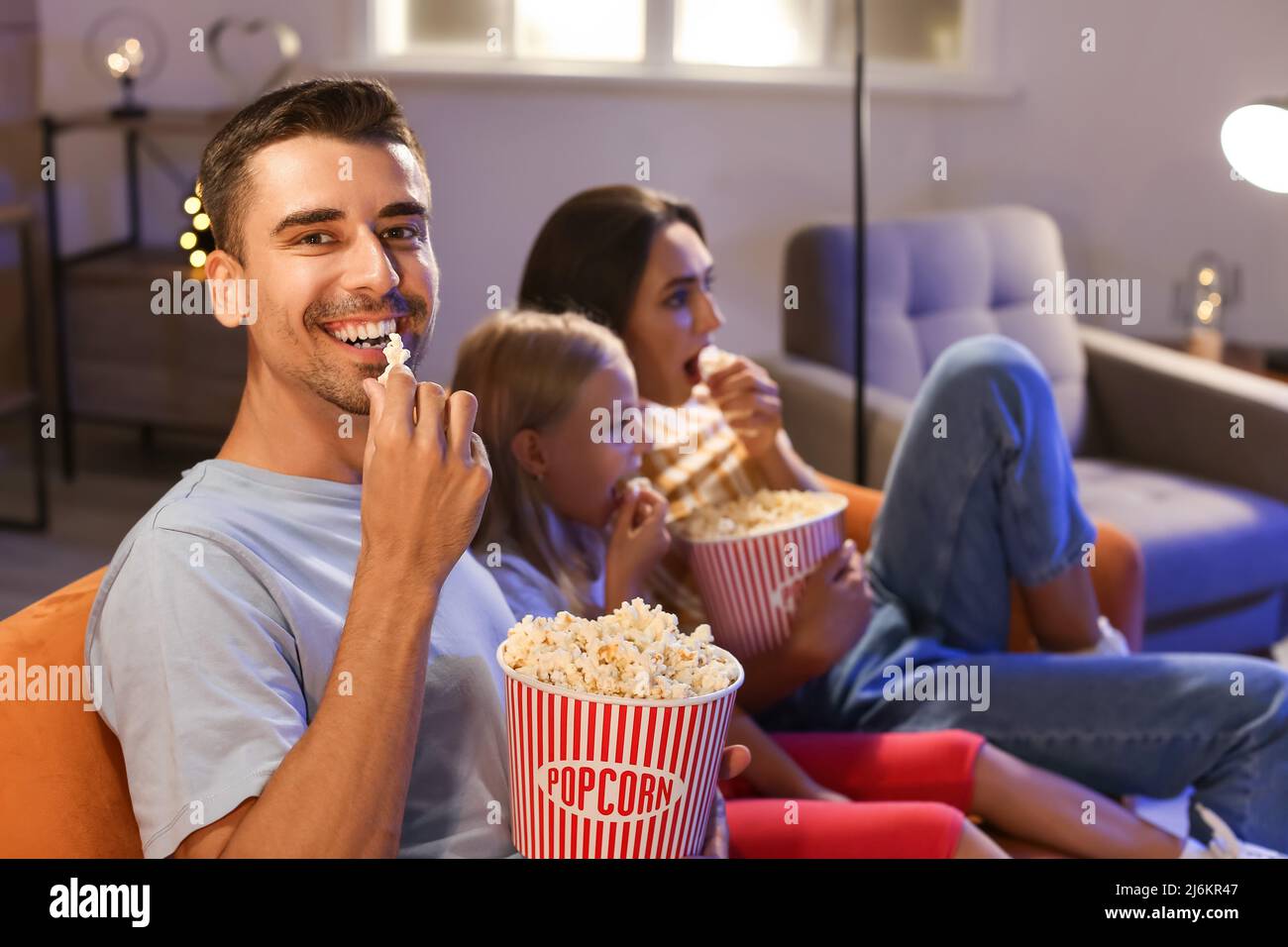 Happy family with popcorn watching movie at home in evening Stock Photo ...