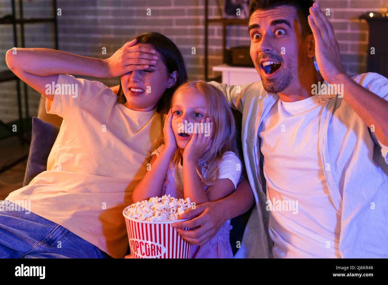 Shocked family with popcorn watching movie at home in evening Stock ...