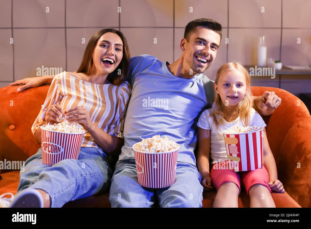 Happy family with popcorn watching movie at home in evening Stock Photo ...