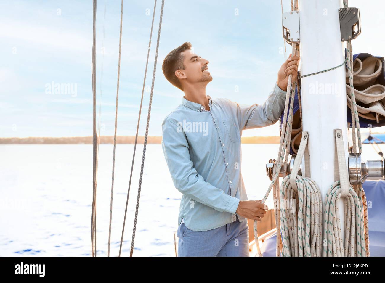 Young man adjusting the rigging of his yacht Stock Photo - Alamy