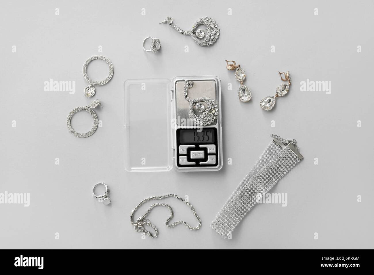 Scales with different jewelry on light background Stock Photo - Alamy