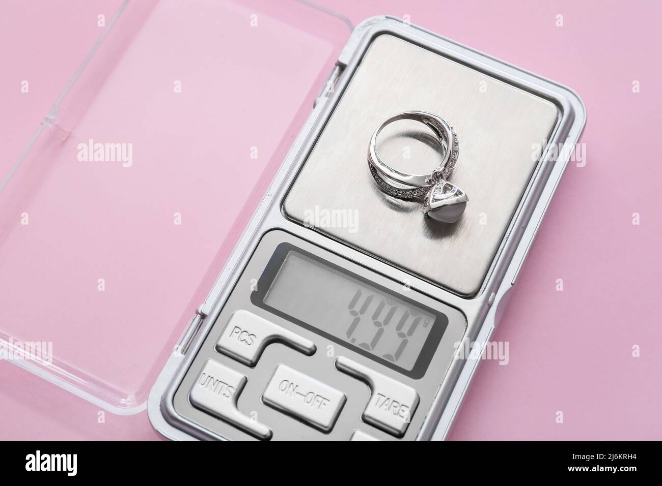 Jewelry scales with ring on pink background Stock Photo - Alamy