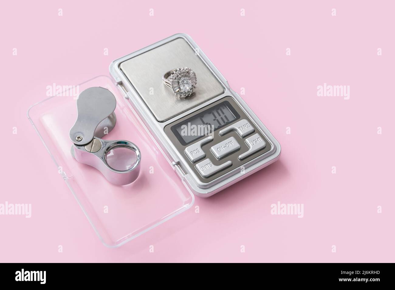Jewelry scales with ring and magnifying glass on pink background Stock ...