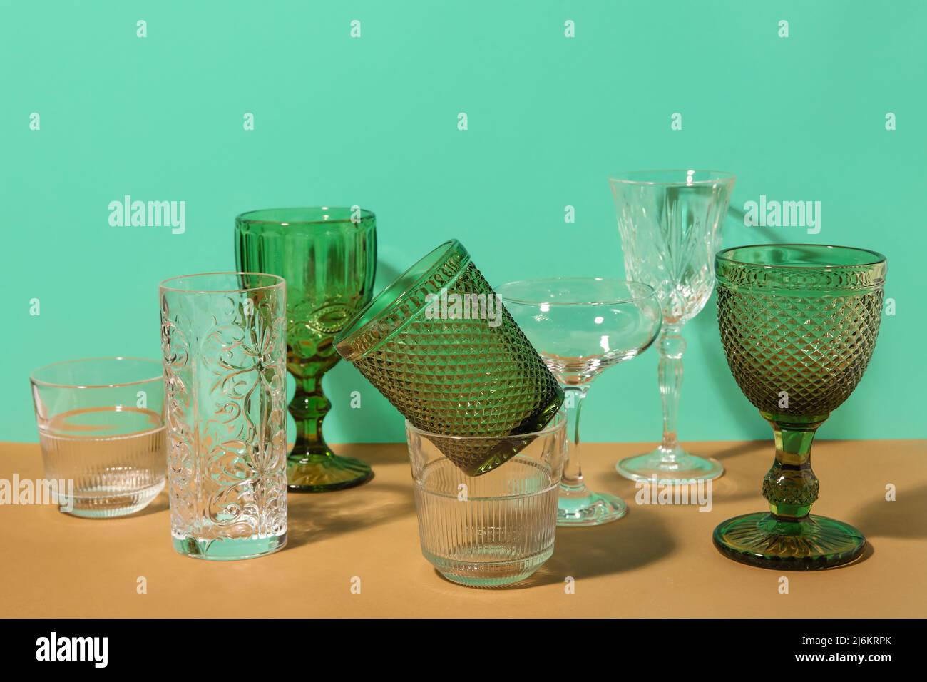 Different empty glasses on color background Stock Photo - Alamy
