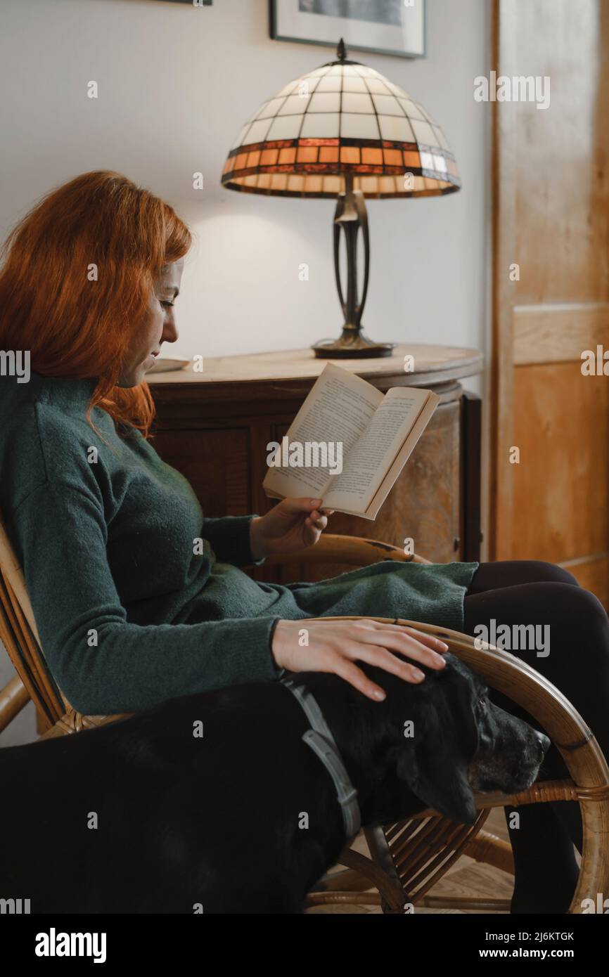 Woman on rocking chair reading book. Relaxed home atmosphere. Vintage ...