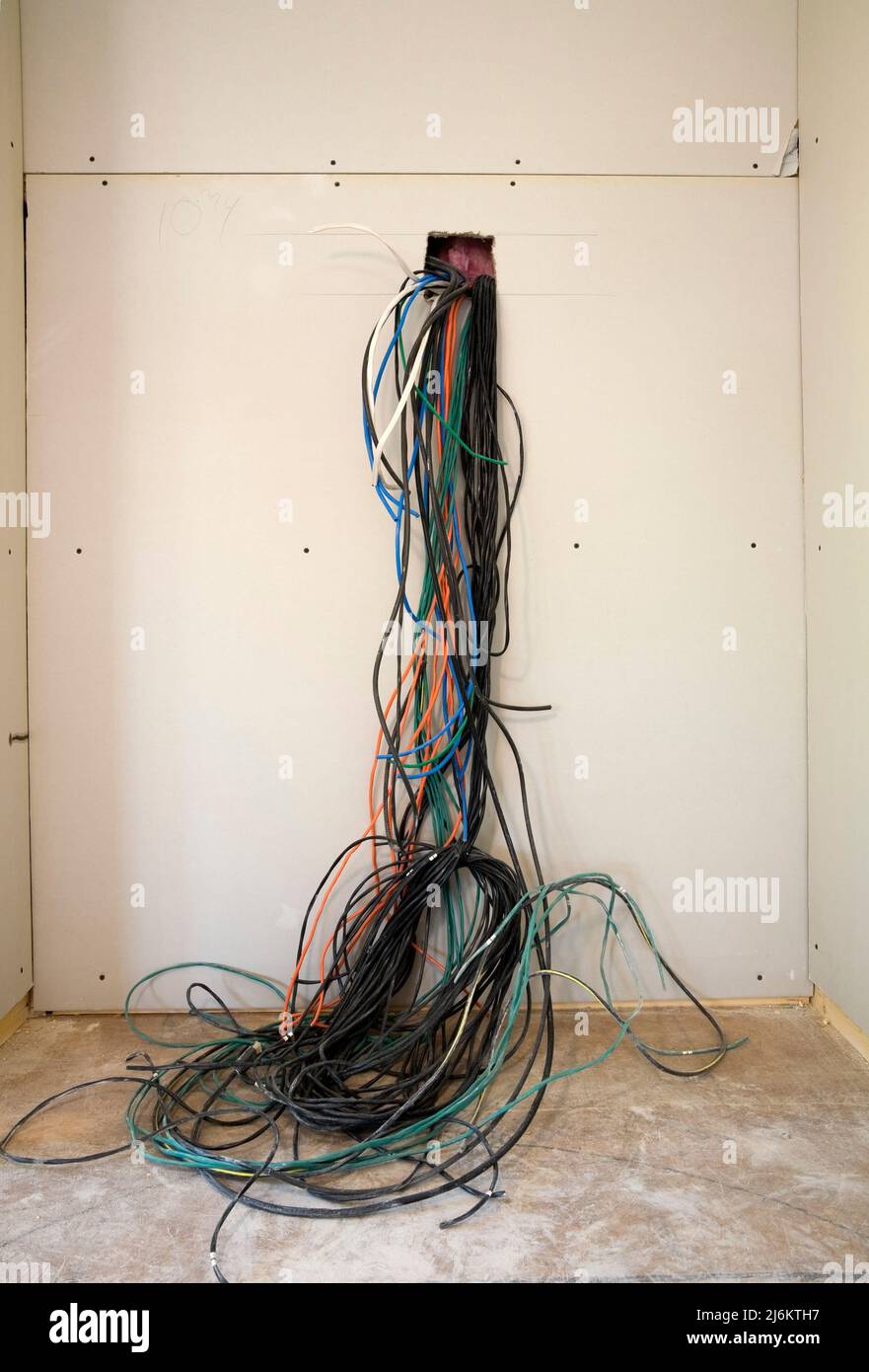 Assorted wires hanging from an opening in an unfinished and unpainted ...
