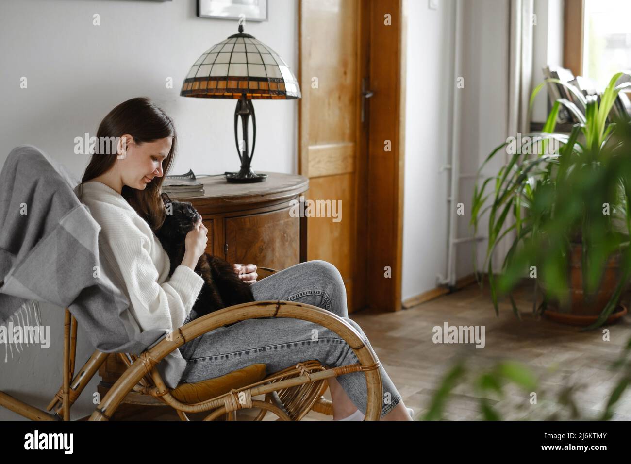 Young woman with black cat sitting on rocking chair. Cozy home ...