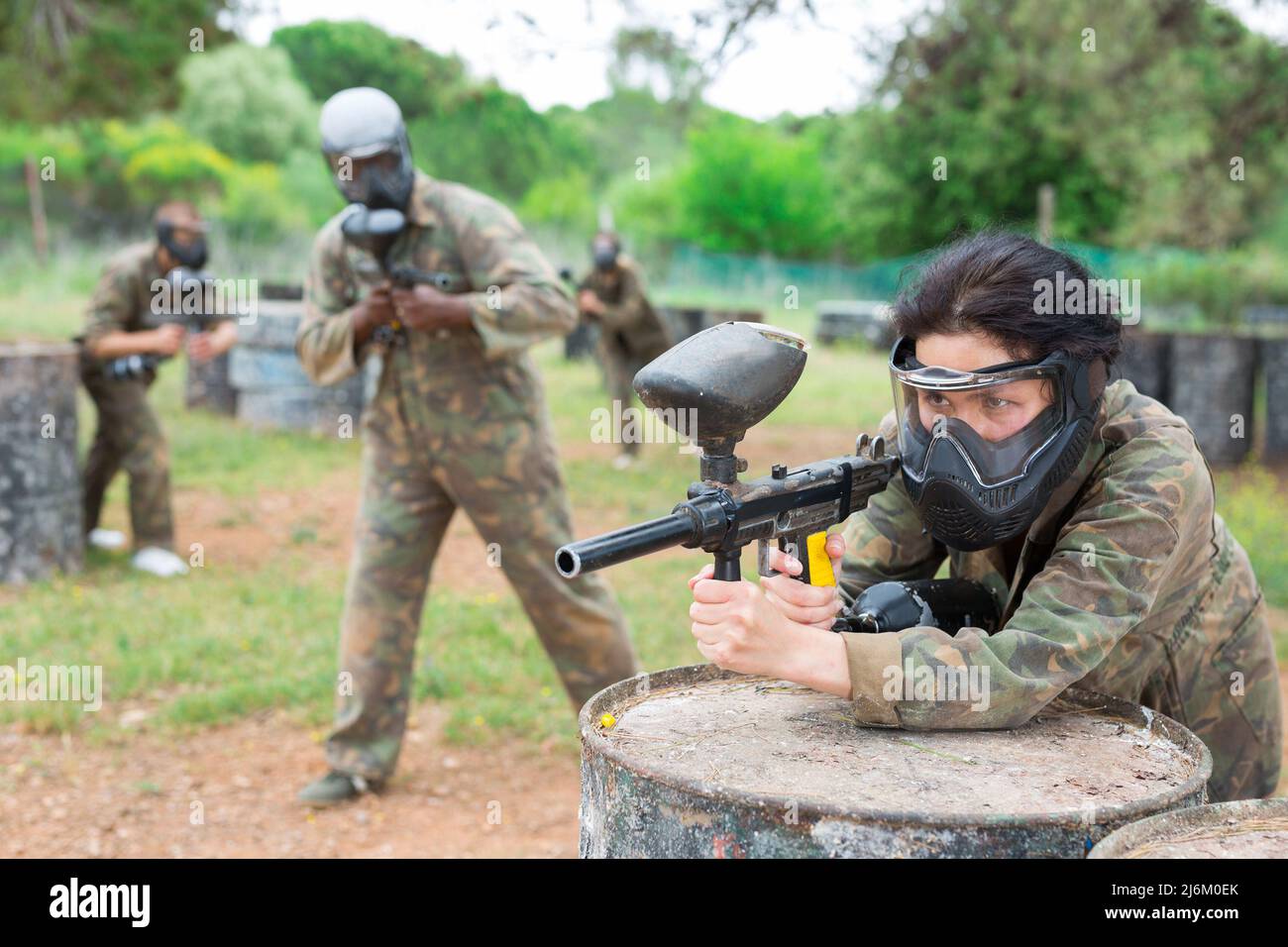 Excited male and female paintball players in protective uniform aiming ...