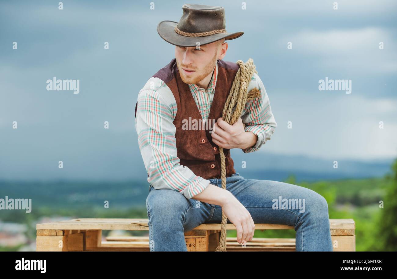 Portrait of farmer or cowboy outdoor. Cowboy with lasso rope on sky ...