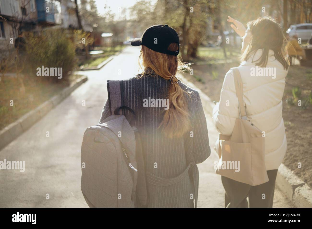 Back view portrait of two women walking and talking in a park asunny ...